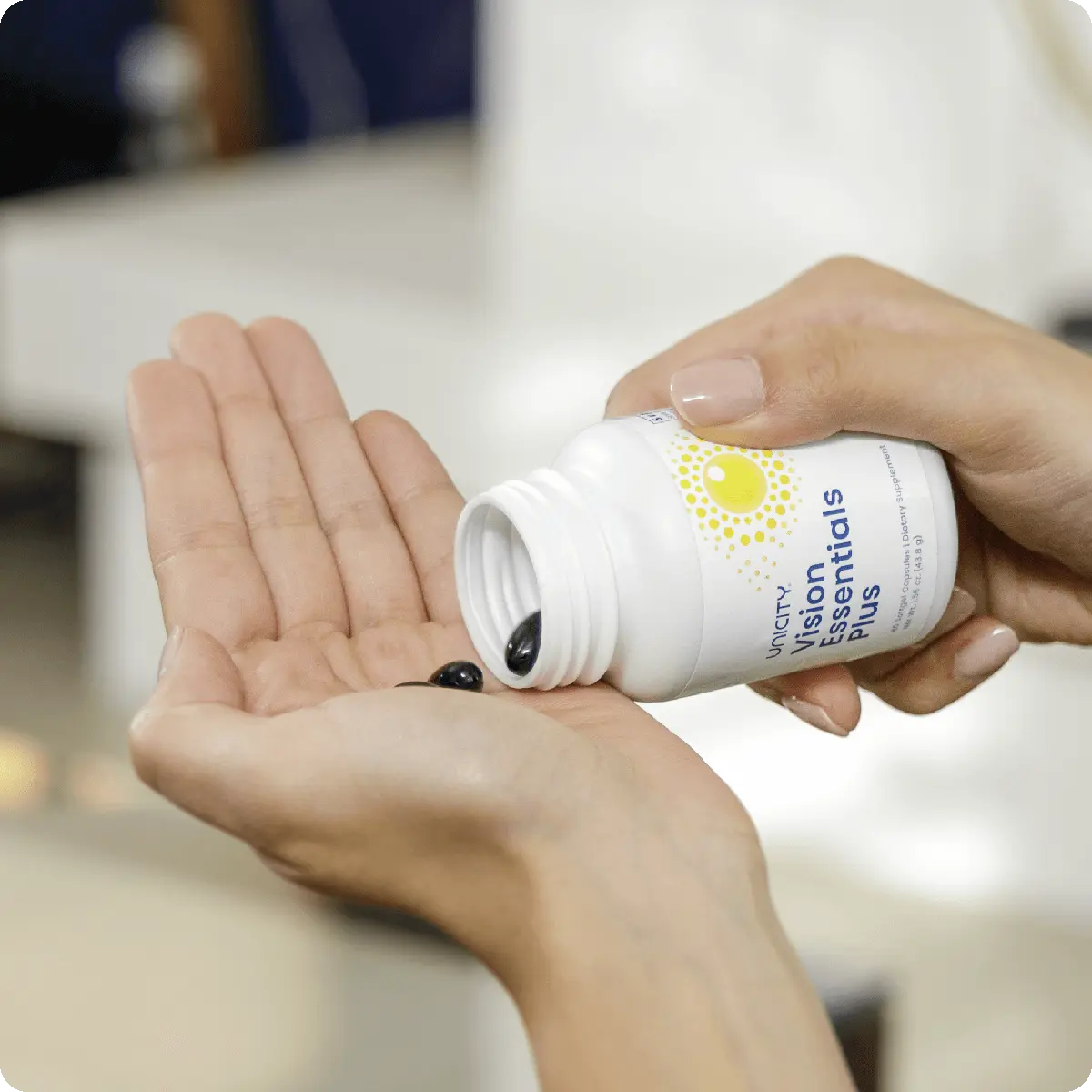 Mujer vertiendo las cápsulas blandas de Vision Essentials Plus en su mano