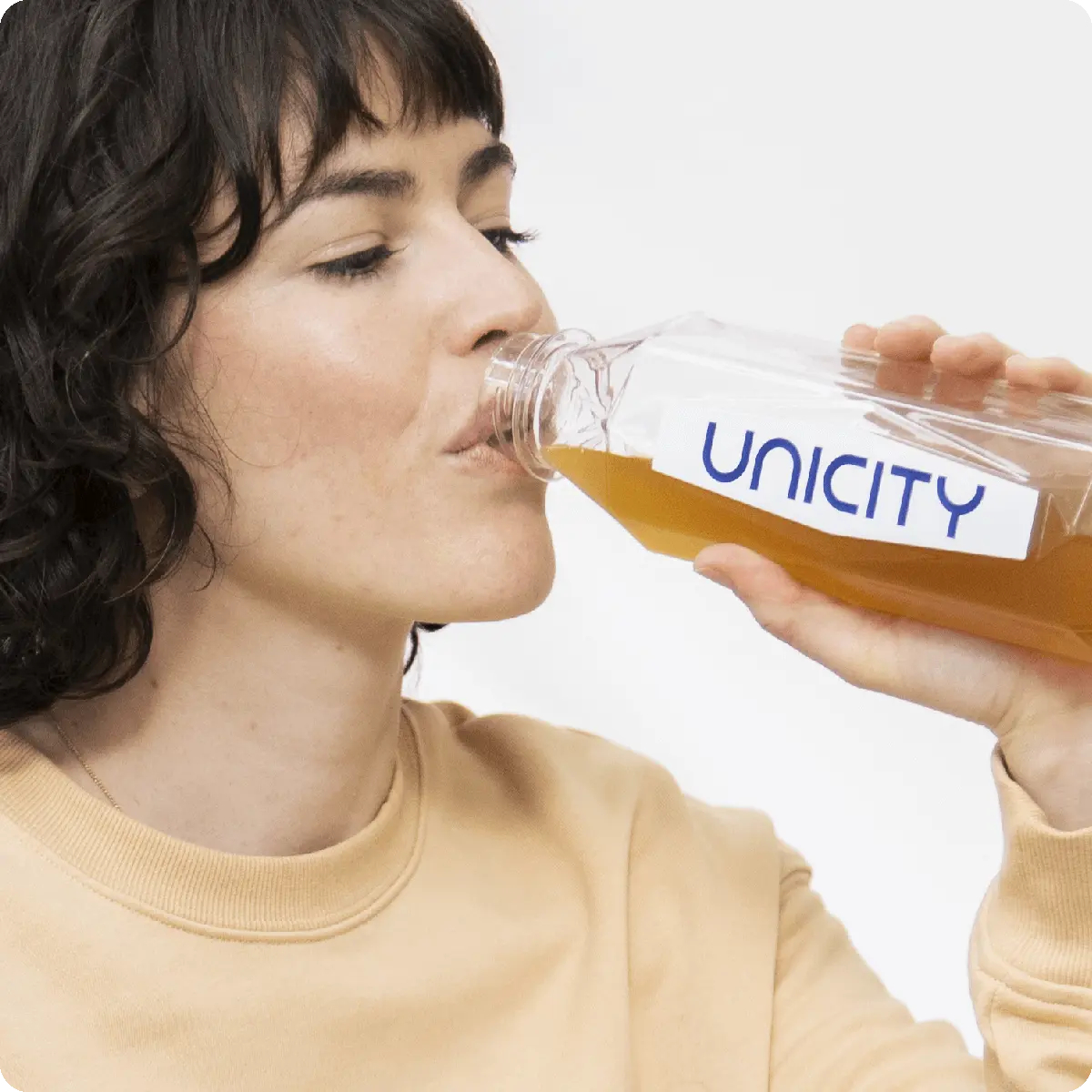Chica bebiendo Unimate de Unicity
